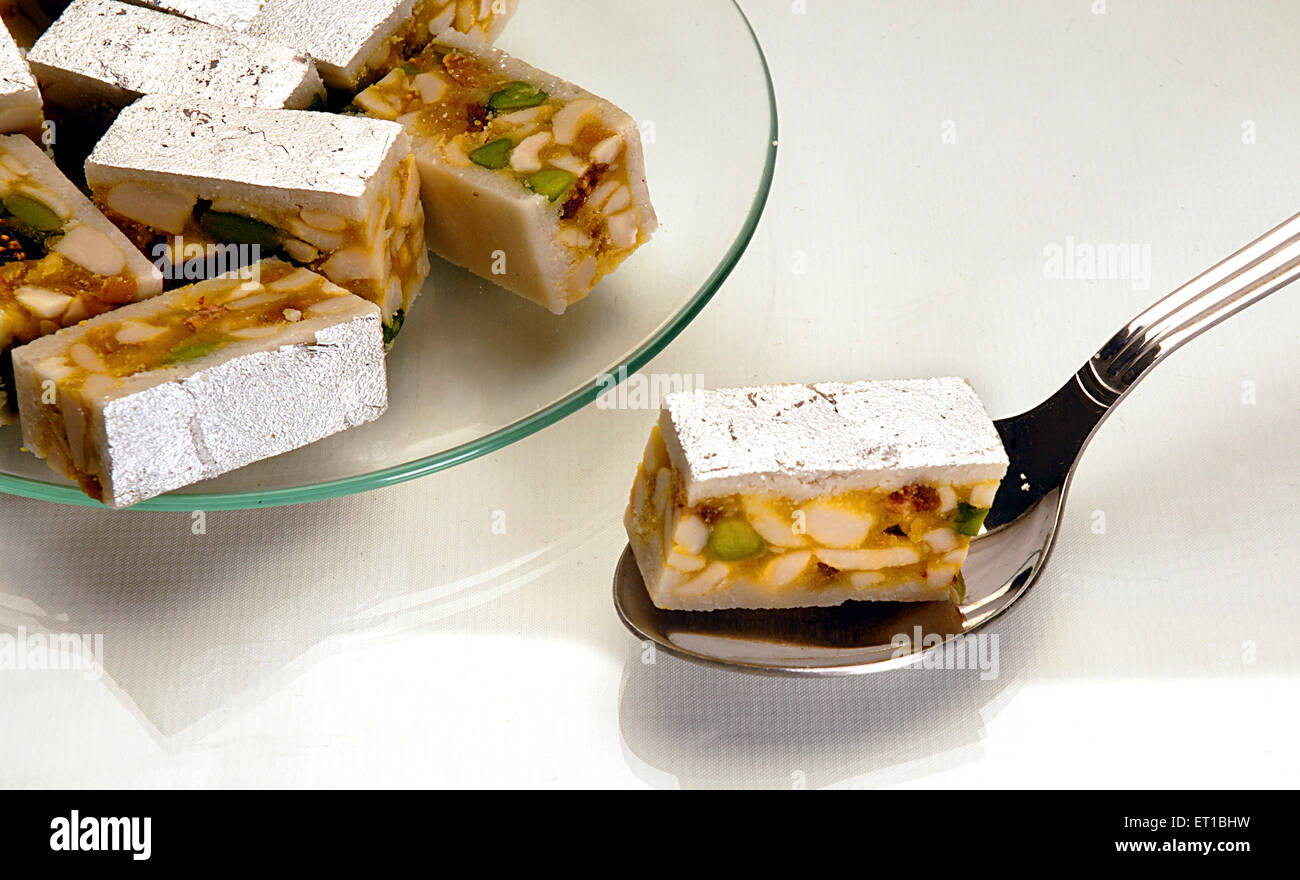 Indian sweet ; panchmeva chakki with silver leaf varakh in spoon on ...