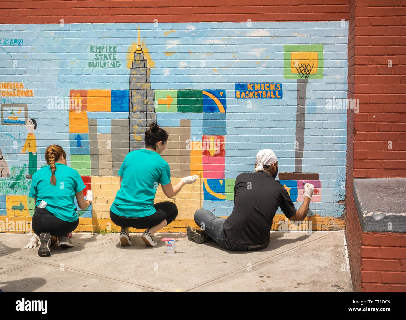 Volunteers touch-up a mural on the side of PS 33 the Chelsea School in ...