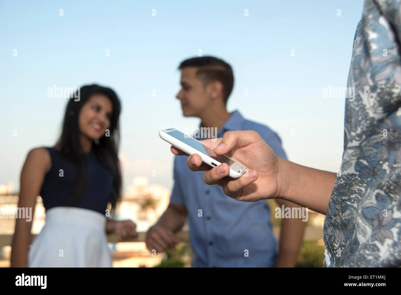 Teenagers checking mobile phone together outdoors Stock Photo - Alamy