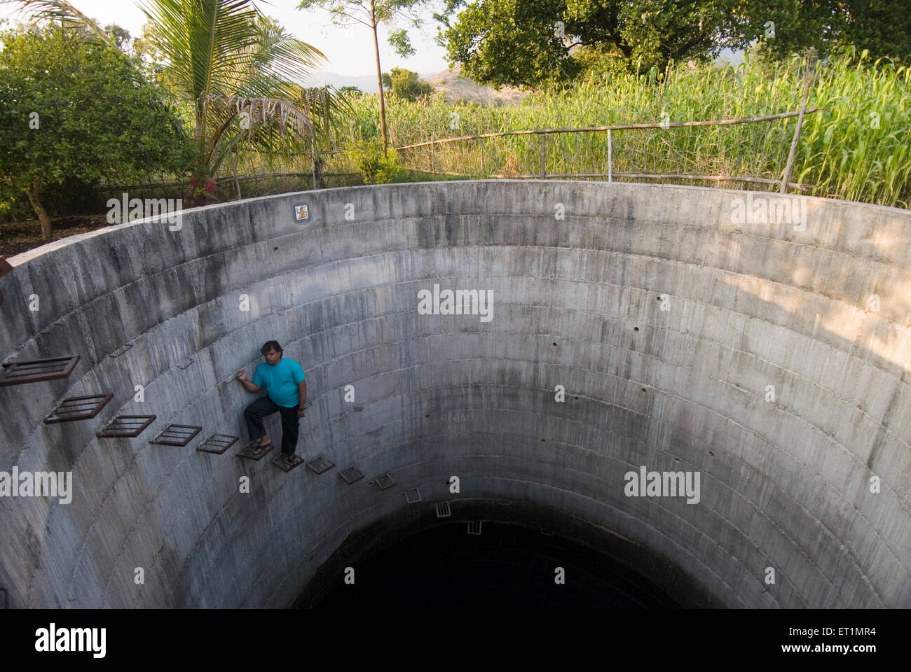 Man standing in cement made well in farm near Wai village ; district ...