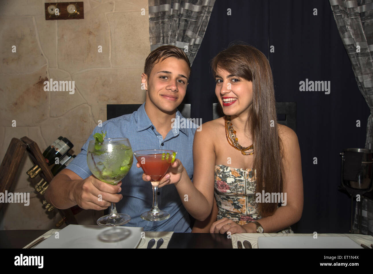 Happy young couple drinking together in restaurant Stock Photo - Alamy