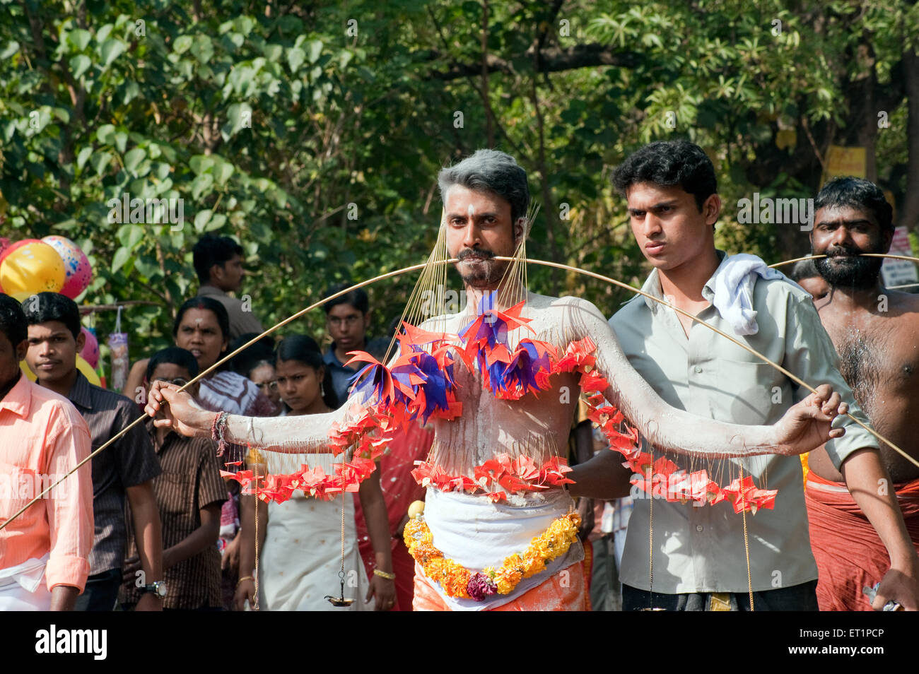 Man piercing spike through cheeks discharging vow in Thaipusam festival ...