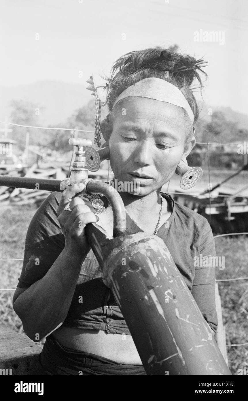 Idu Mishmi lady filling bamboo pipe with water ; Hill Miri tribe ...