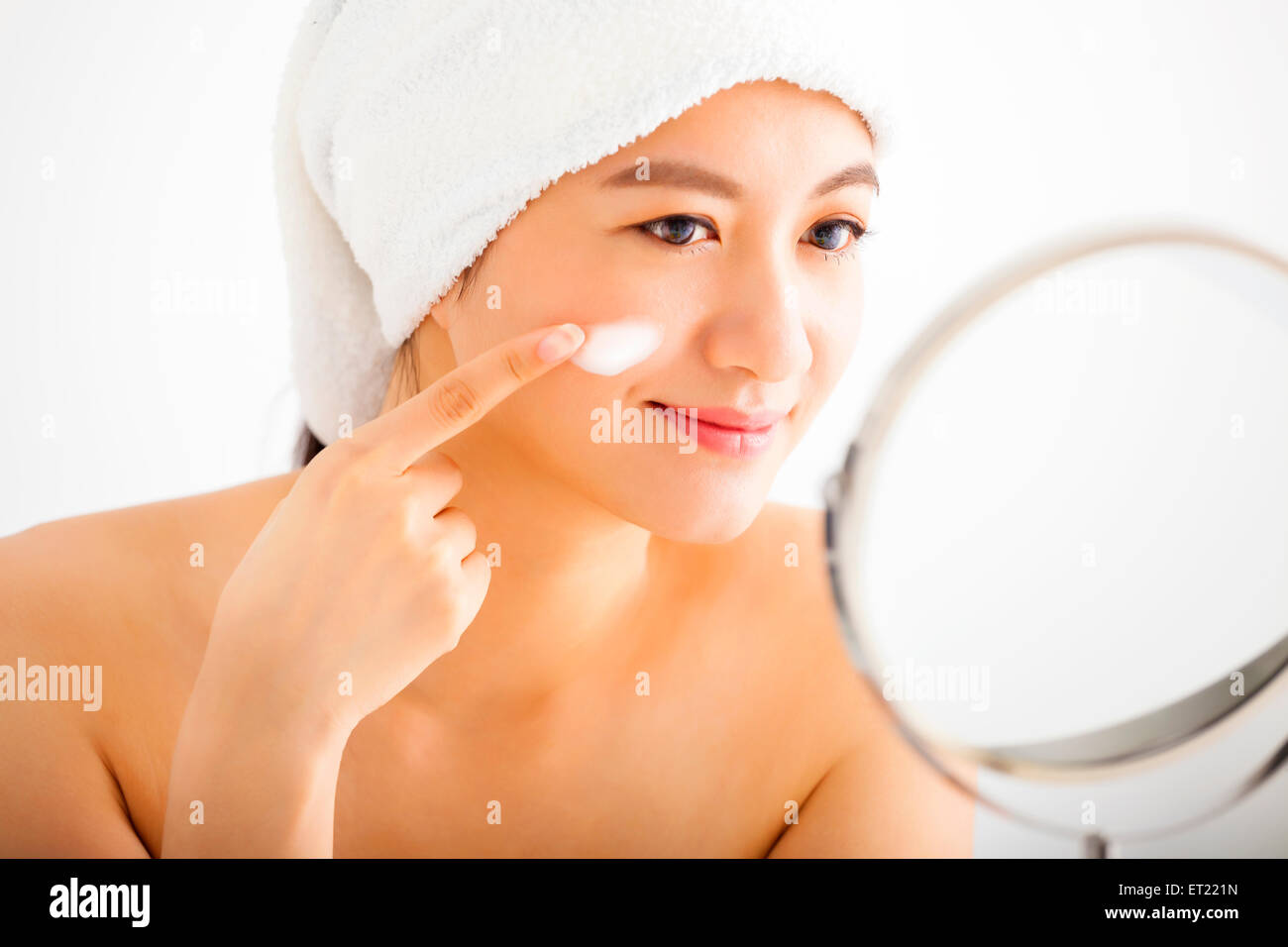 smiling woman applying cream lotion on face Stock Photo - Alamy