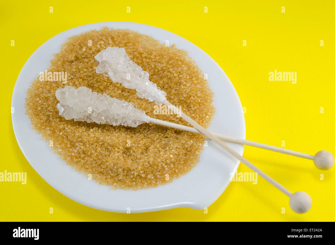 Two sugar sticks containing white and brown sugar with yellow ...
