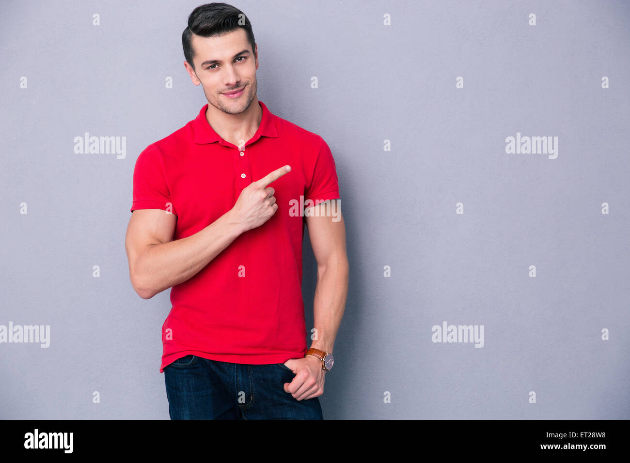 Portrait of a casual man pointing away over gray background Stock Photo ...