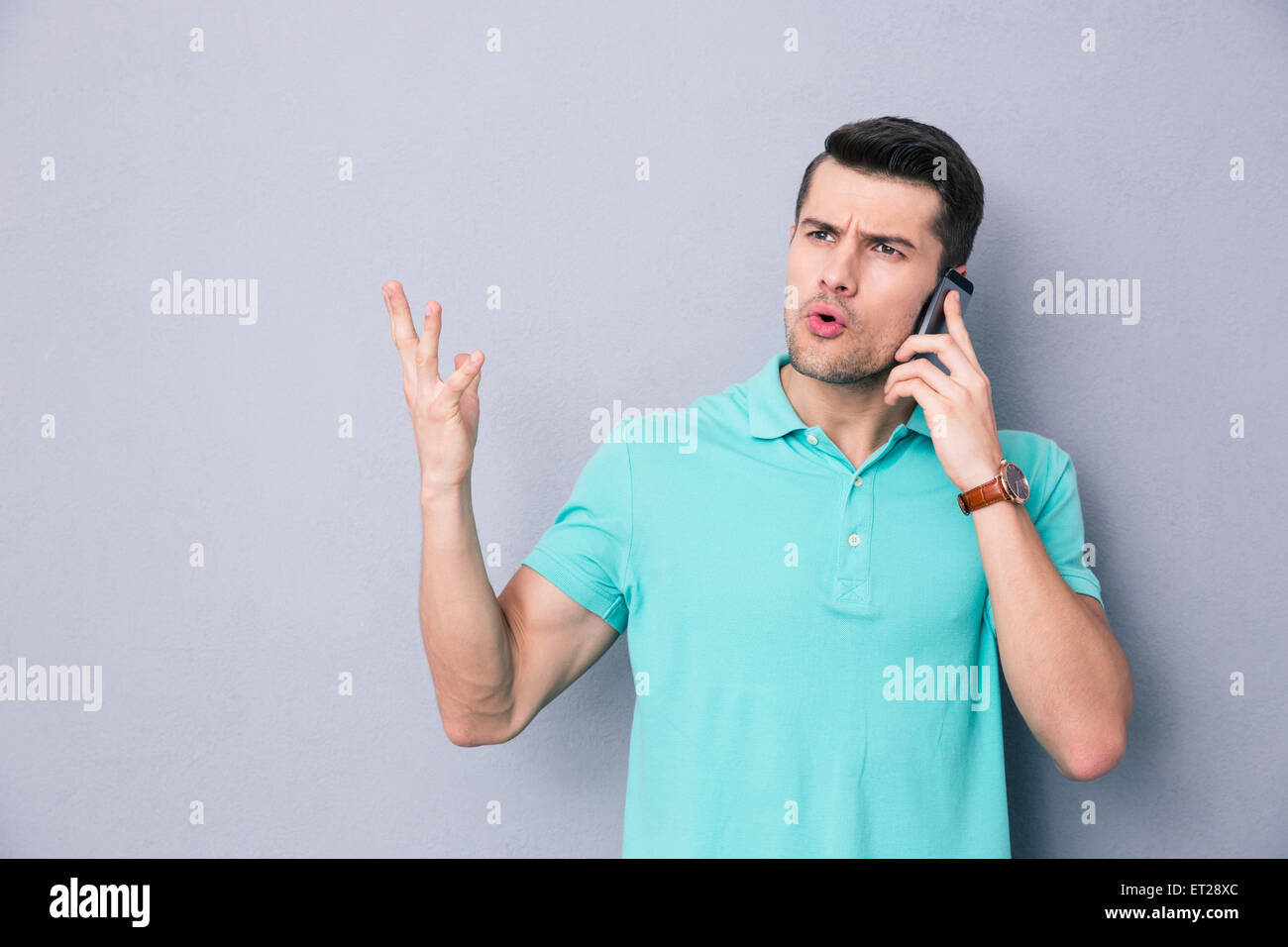 Young man talking on the phone over gray background Stock Photo - Alamy