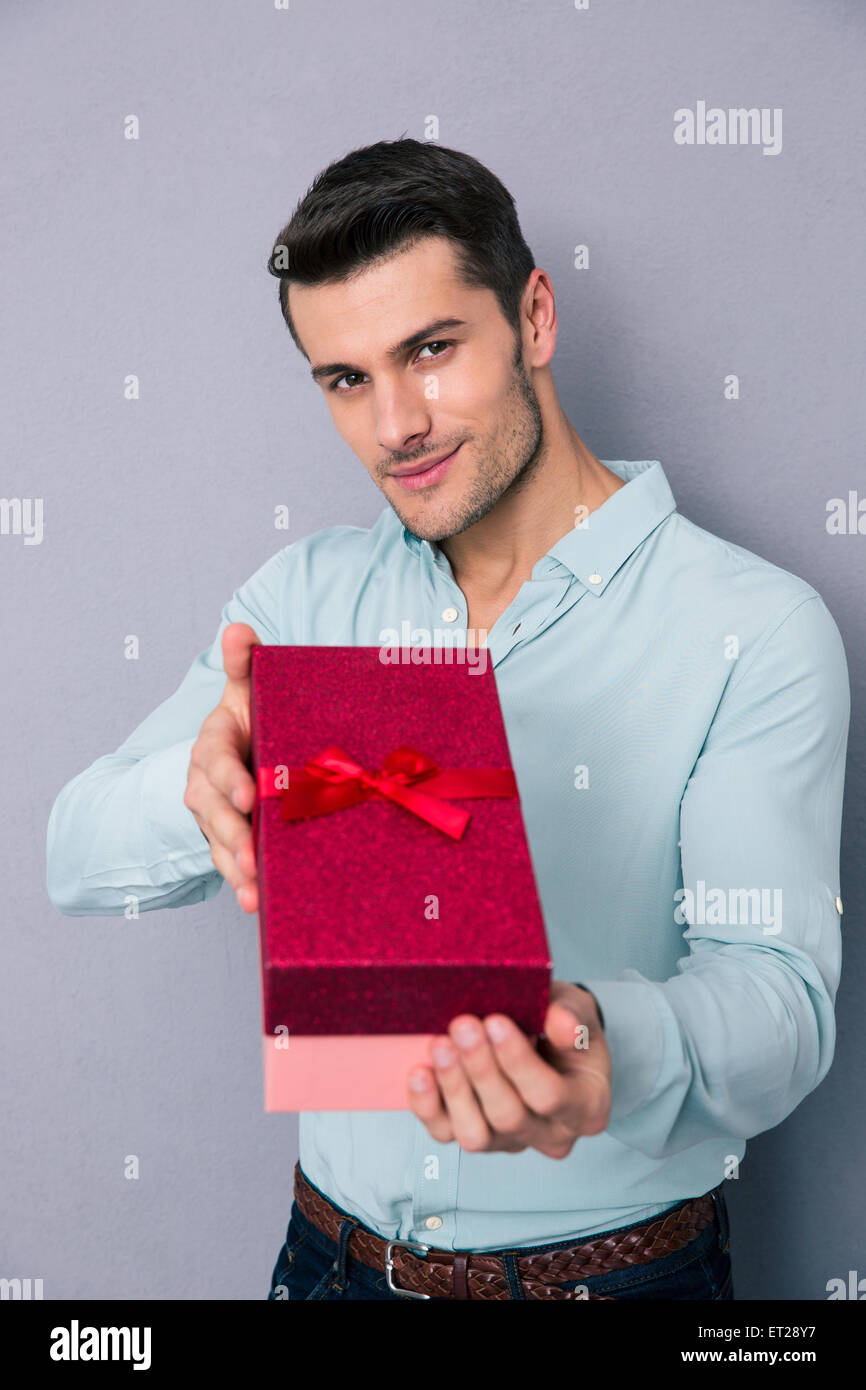 Happy man giving gift box on camera over gray background Stock Photo ...