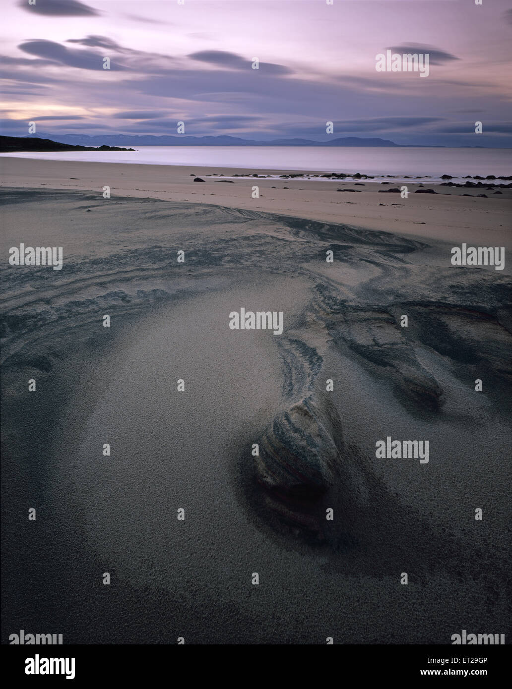 Sand patterns at the back of a beach where a river flows carrying ...