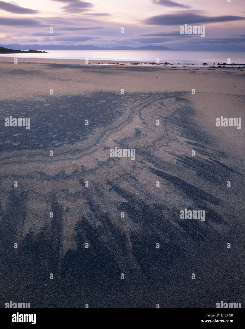 Sand patterns at the back of a beach where a river flows carrying ...