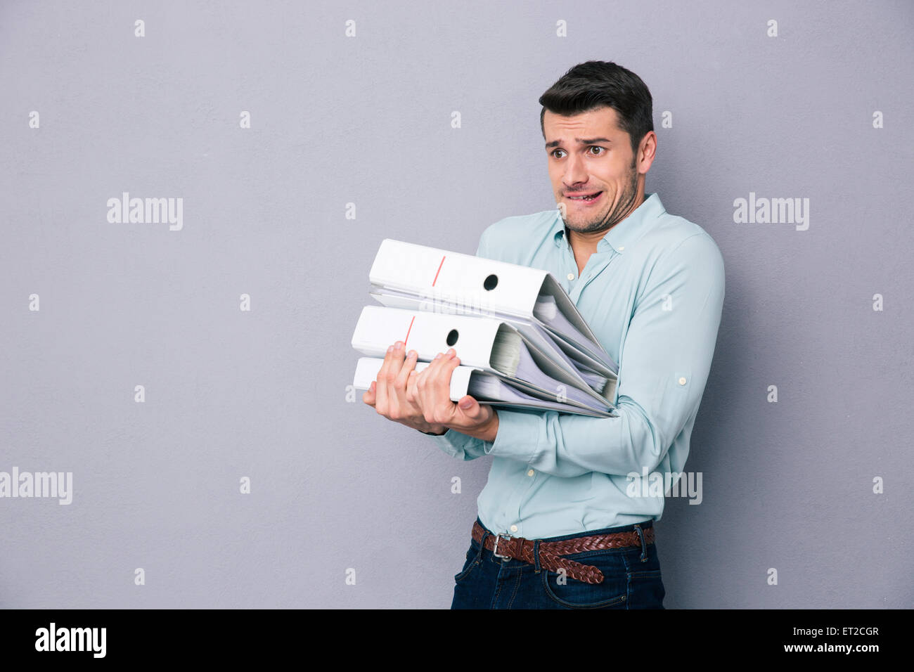 Casual man holding folders over gray background Stock Photo - Alamy