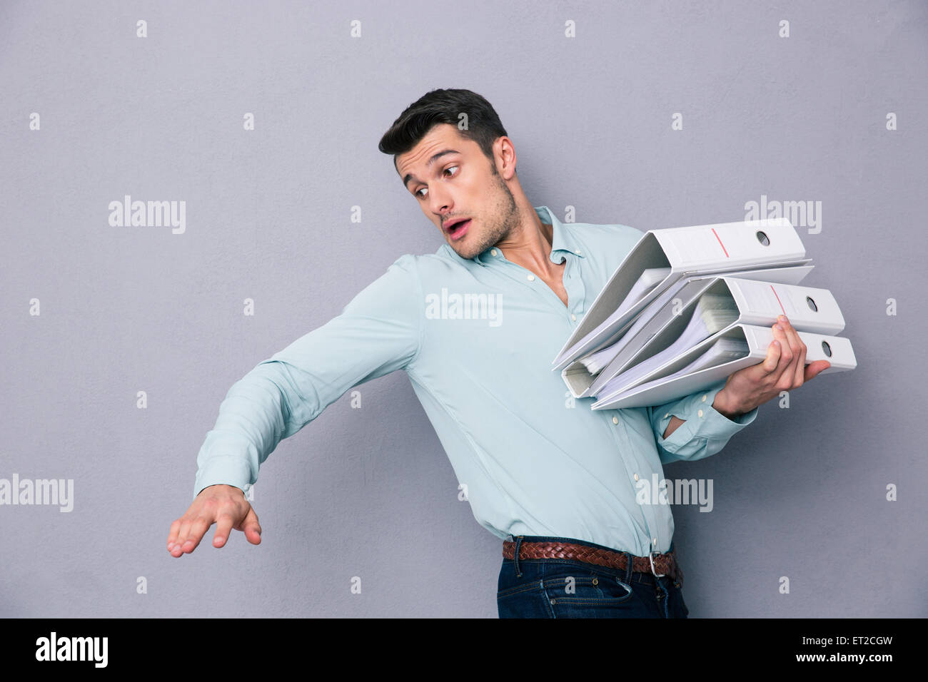 Young man holding folders over gray background Stock Photo - Alamy