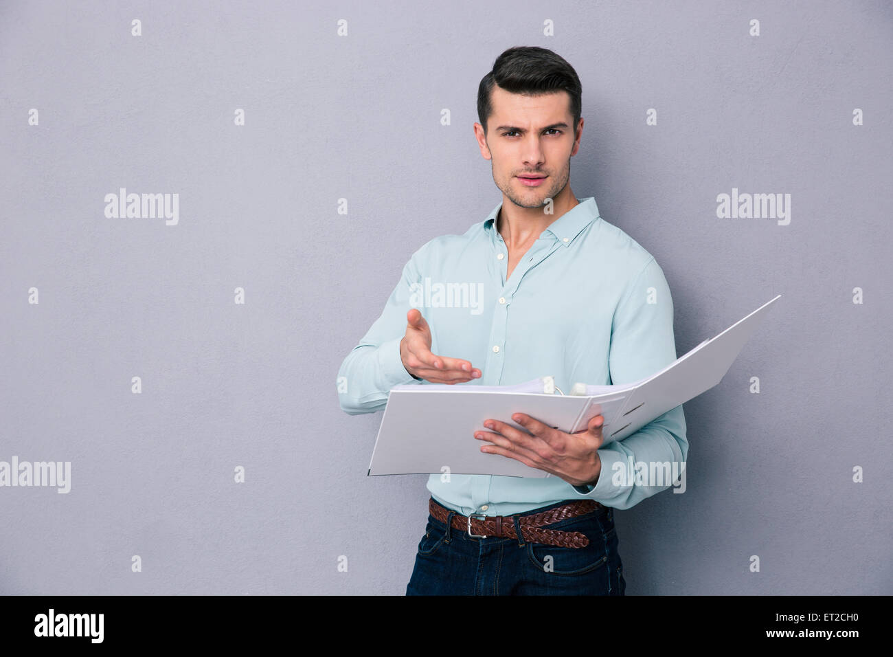 Handsome young man reading documents over gray background Stock Photo ...