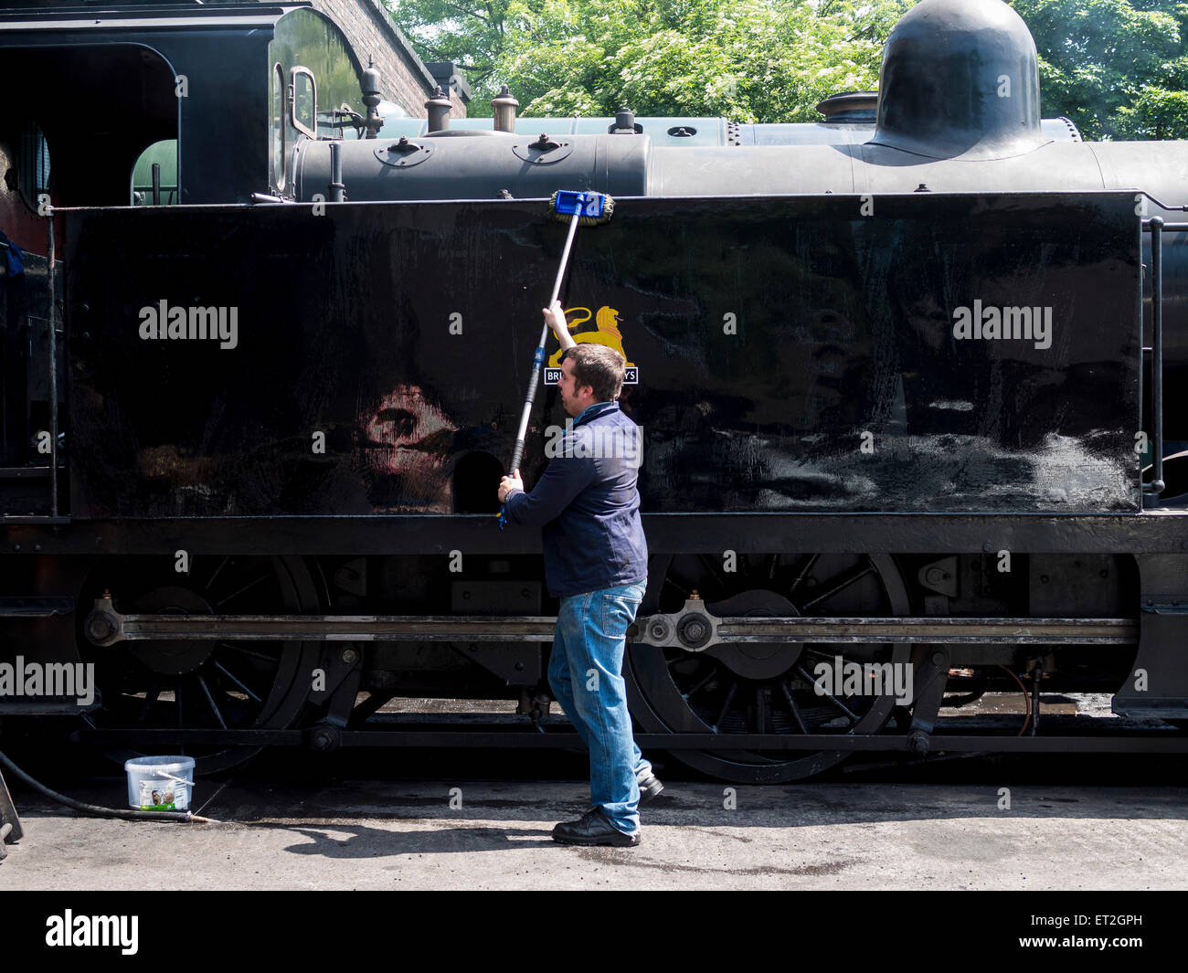 man washes down a vintage steam locomotive at Loughborough station, on ...