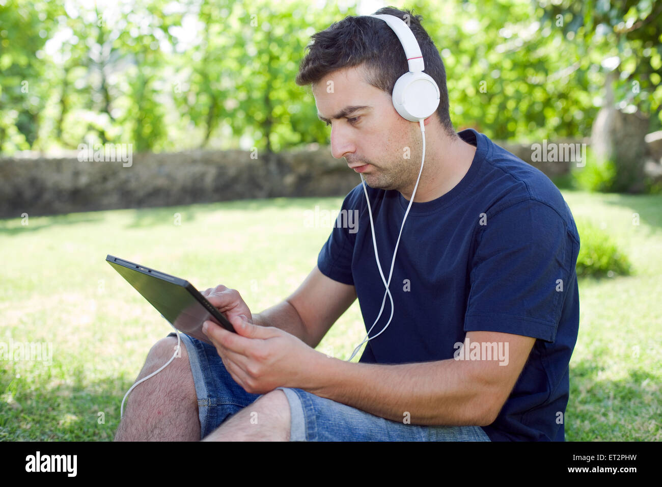 young man holding a tablet with headphones, outdoor Stock Photo - Alamy