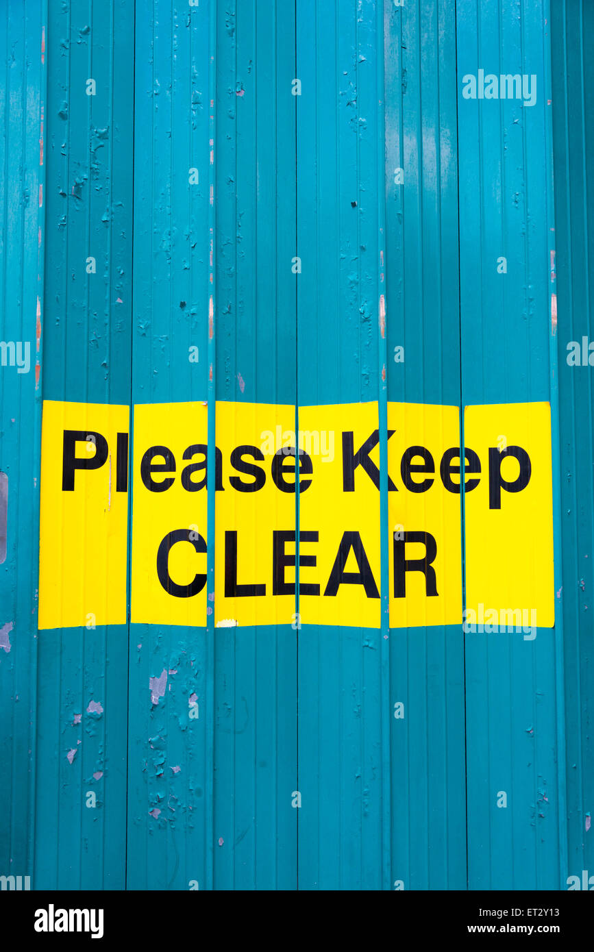 A please keep clear sign on a folding door on a commercial building ...