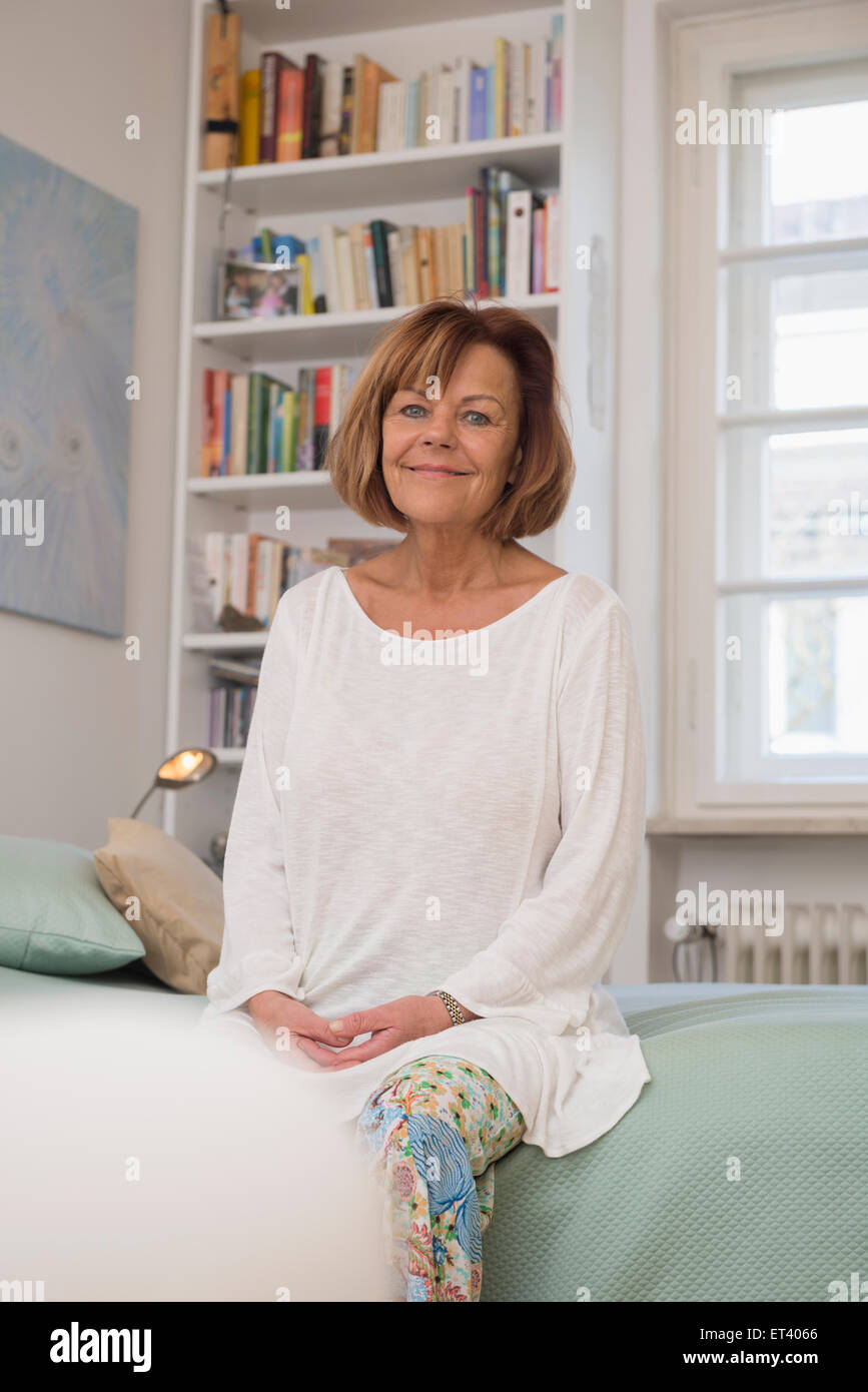 Senior woman sitting on bed and smiling, Munich, Bavaria, Germany Stock ...