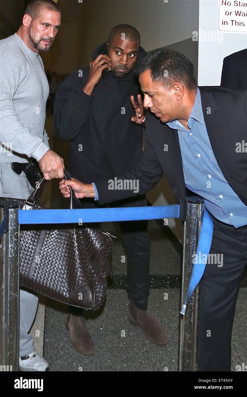 Kanye West talking on his cellphone as he leaves on a flight from Los ...