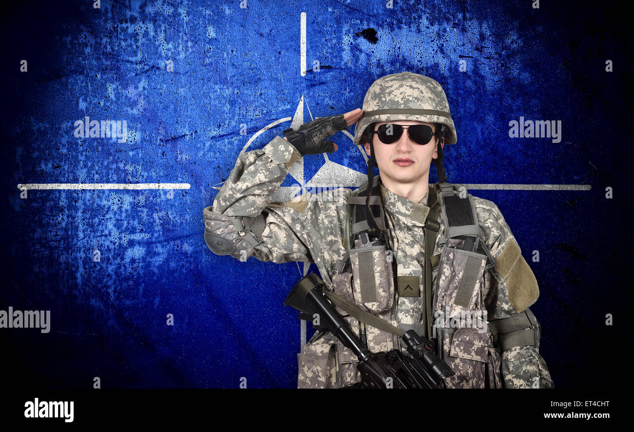 soldier salutes the Nato flag on the background Stock Photo - Alamy