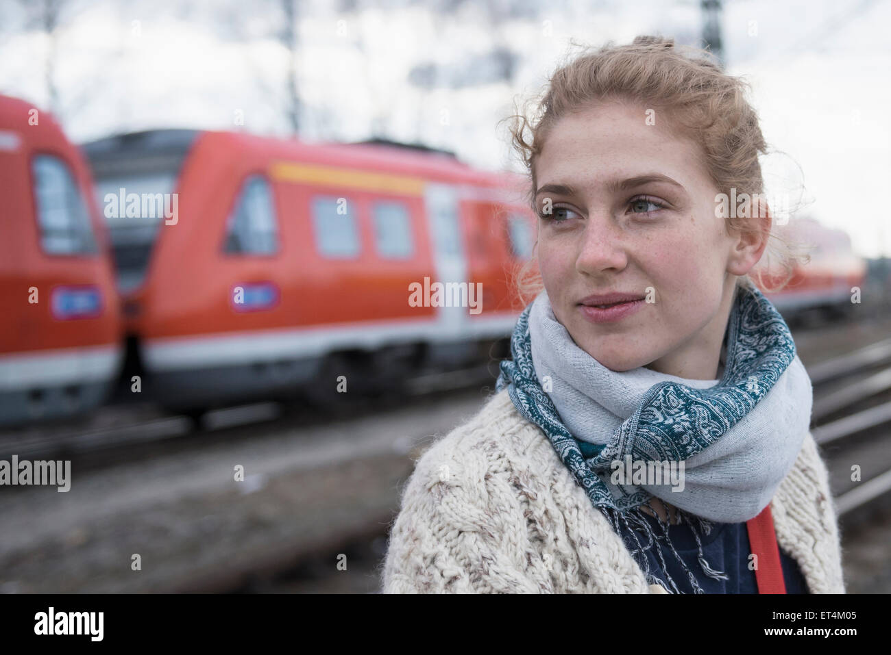 Portrait of a young woman with railway track and red train in the ...