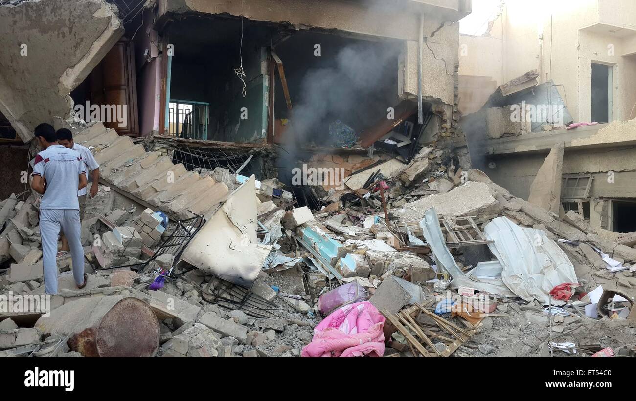 Fallujah, Iraq. 11th June, 2015. Two men stand near a damaged building ...