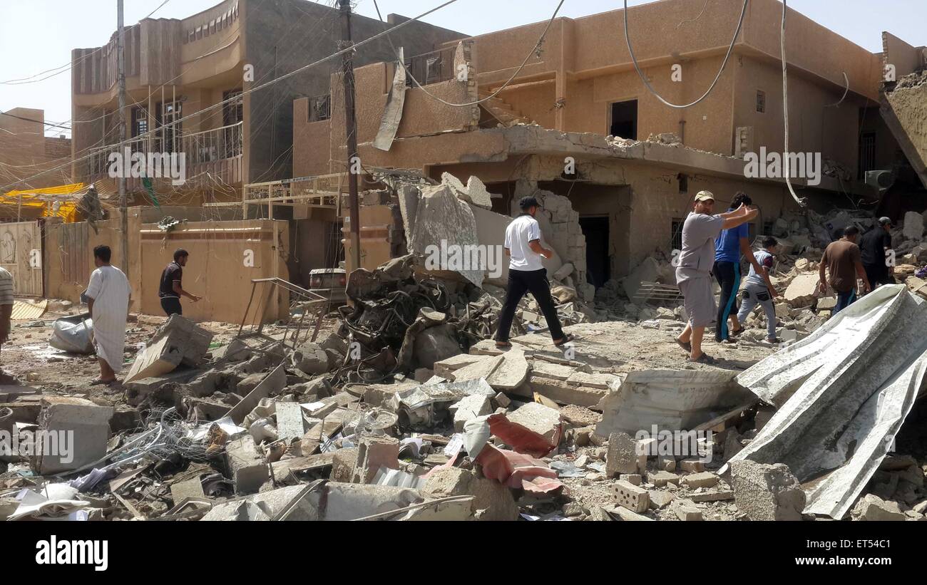 Fallujah, Iraq. 11th June, 2015. People gather near a damaged building ...