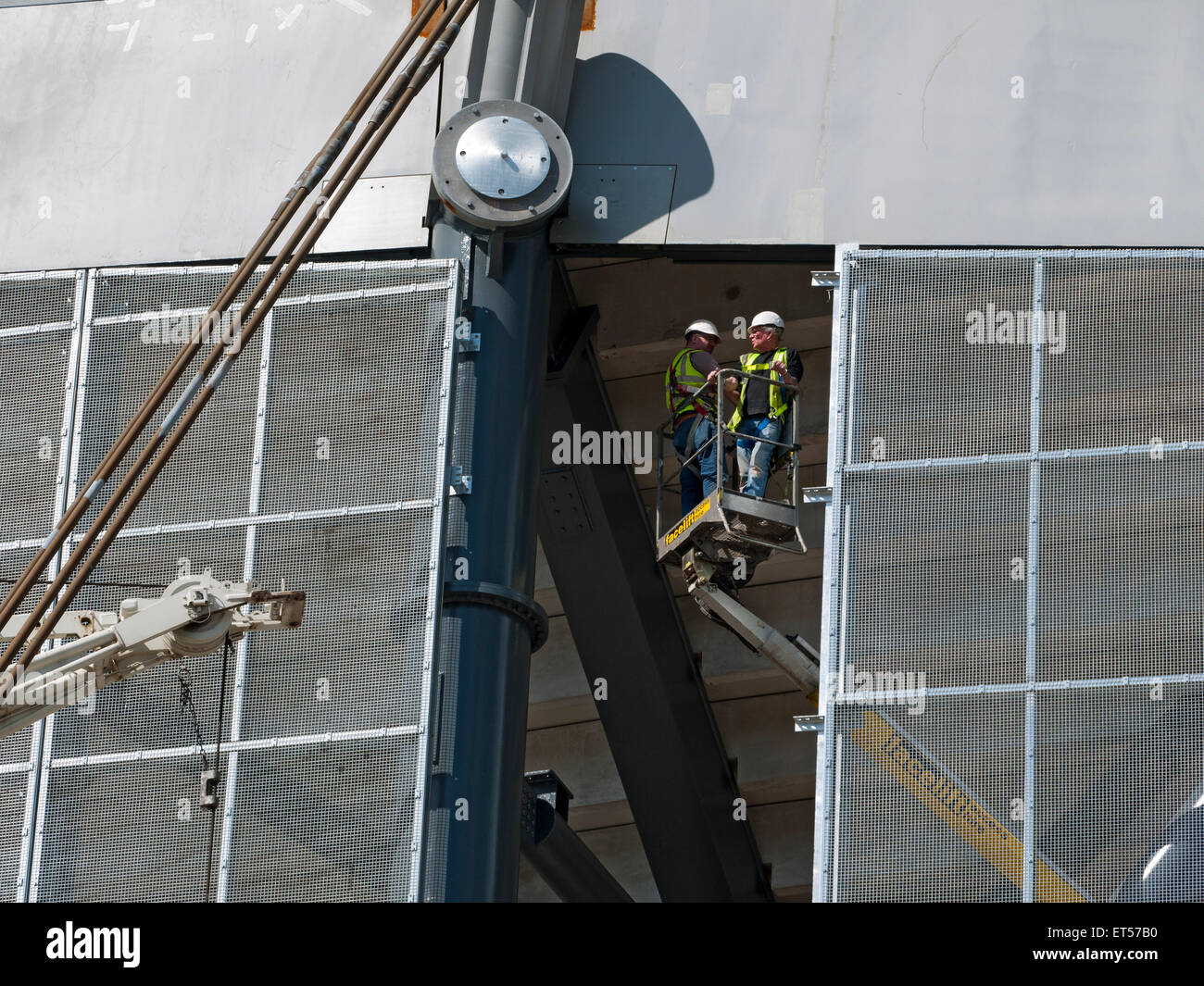Workmen on an access platform installing mesh panels, South Stand ...