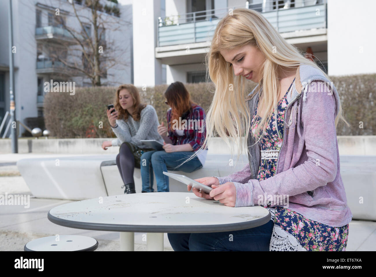 Teenage girl using digital tablet with her friends using technology in ...