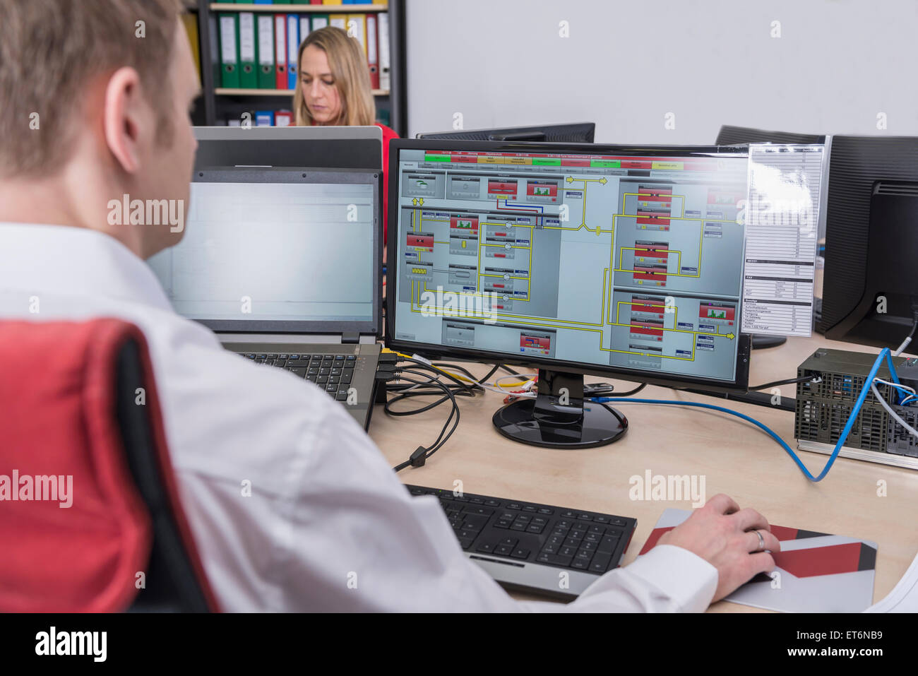Man working in office with his colleague in background, Munich, Bavaria ...