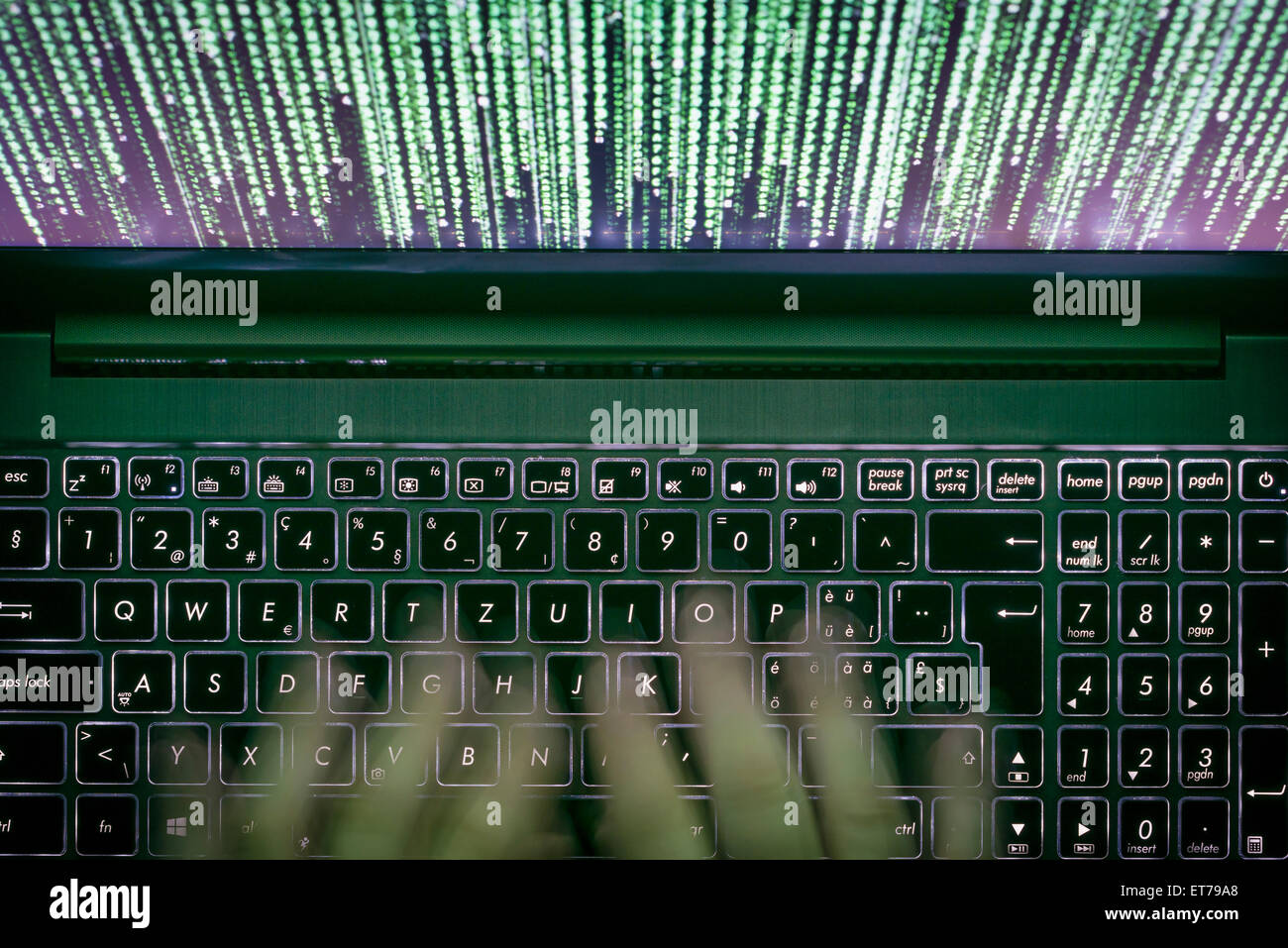 Hands are typing on a laptop computer in the dark with illuminated ...