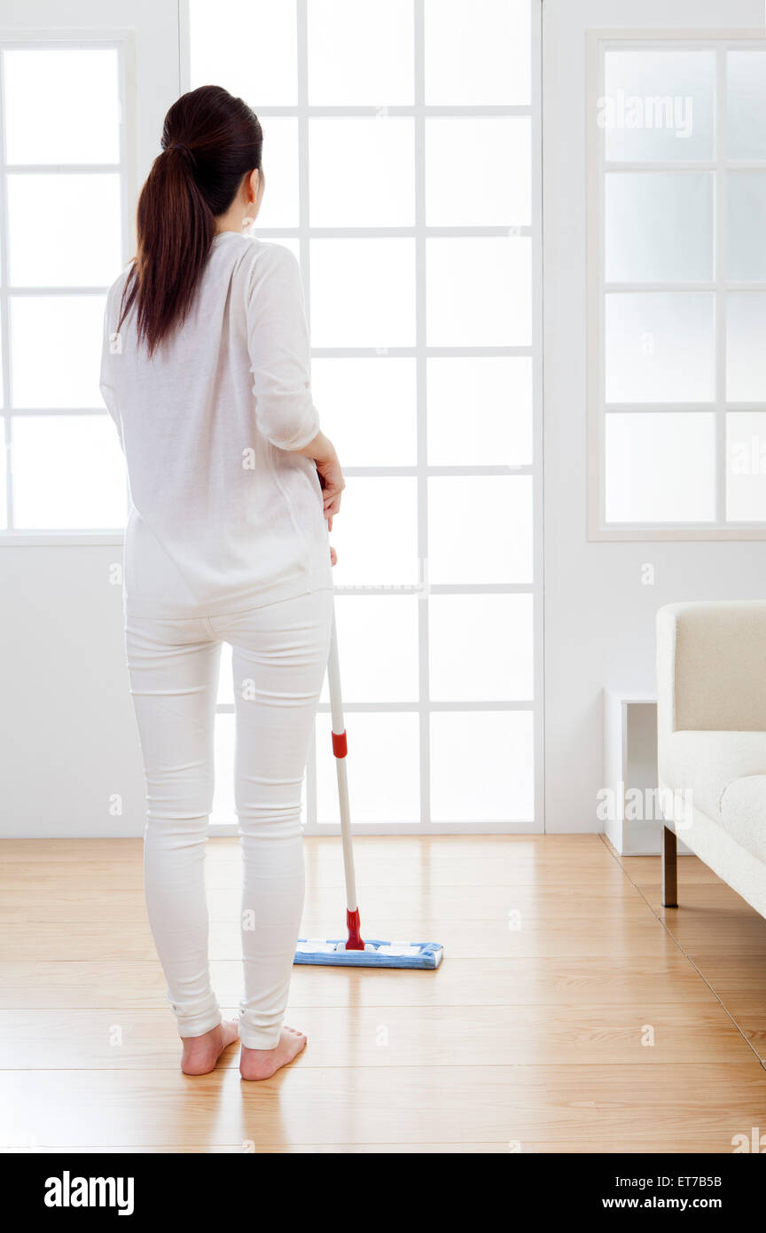 Young woman holding mop and standing with rear view Stock Photo - Alamy