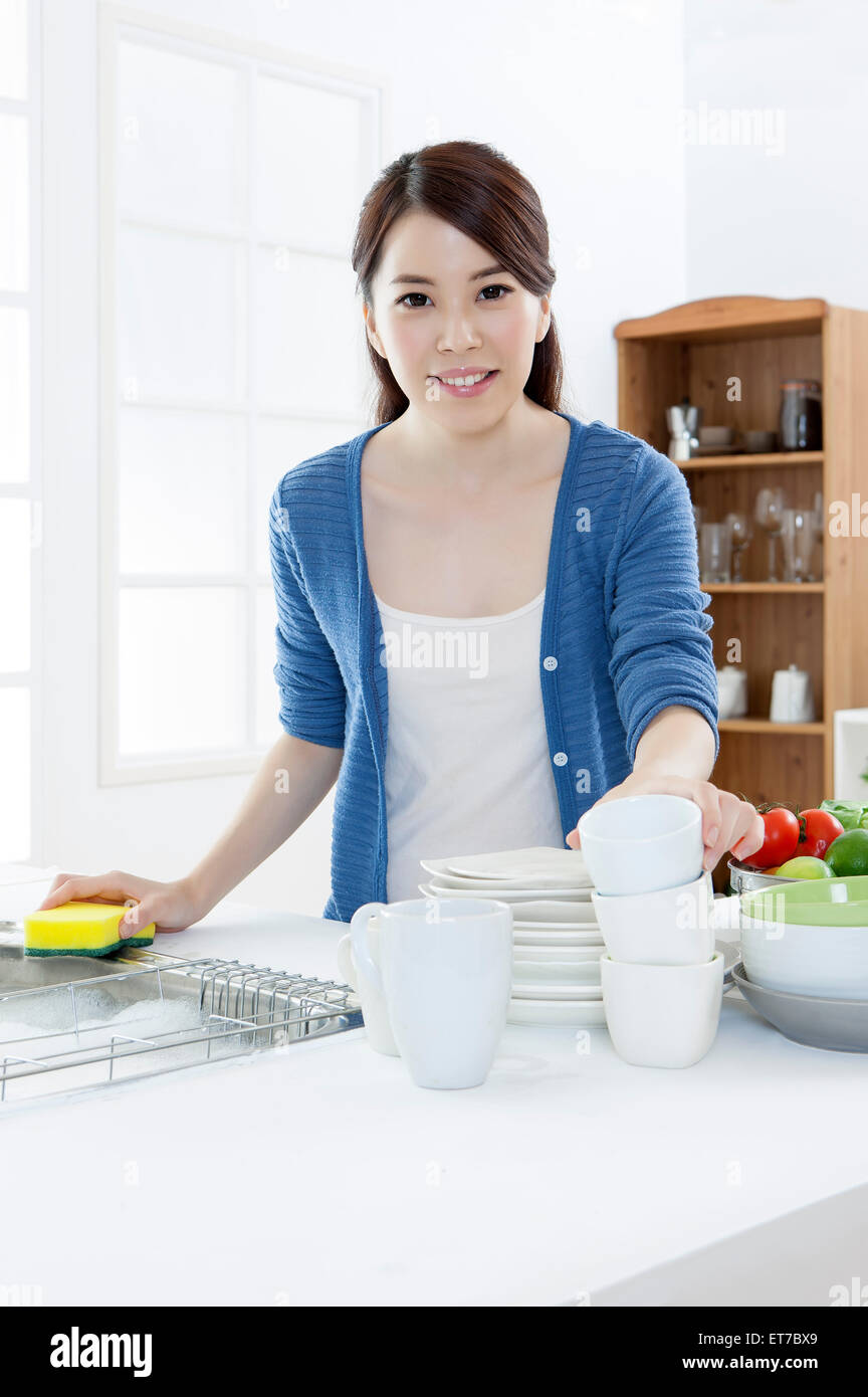 Young woman washing cups and smiling at the camera Stock Photo - Alamy