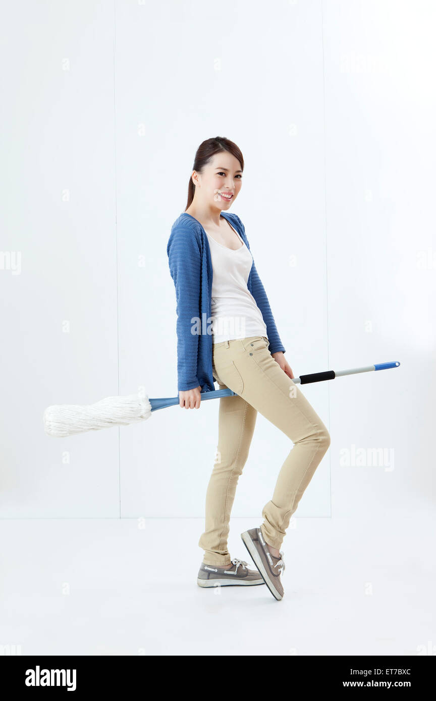 Young woman holding mop and smiling at the camera Stock Photo - Alamy