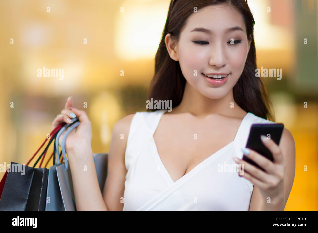 Young woman holding shopping bags and mobile phone Stock Photo - Alamy