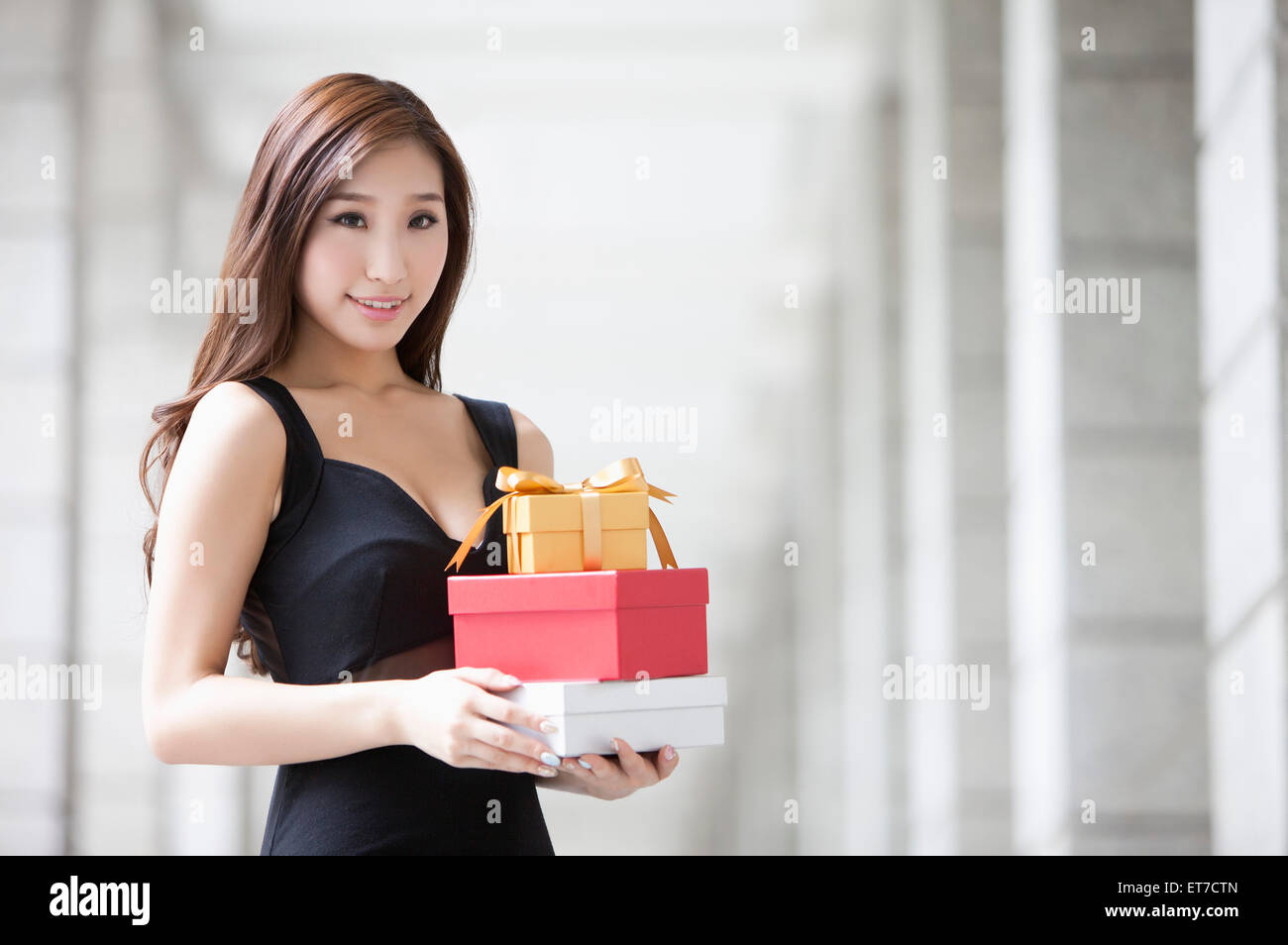 Young woman holding gifts with smile Stock Photo - Alamy
