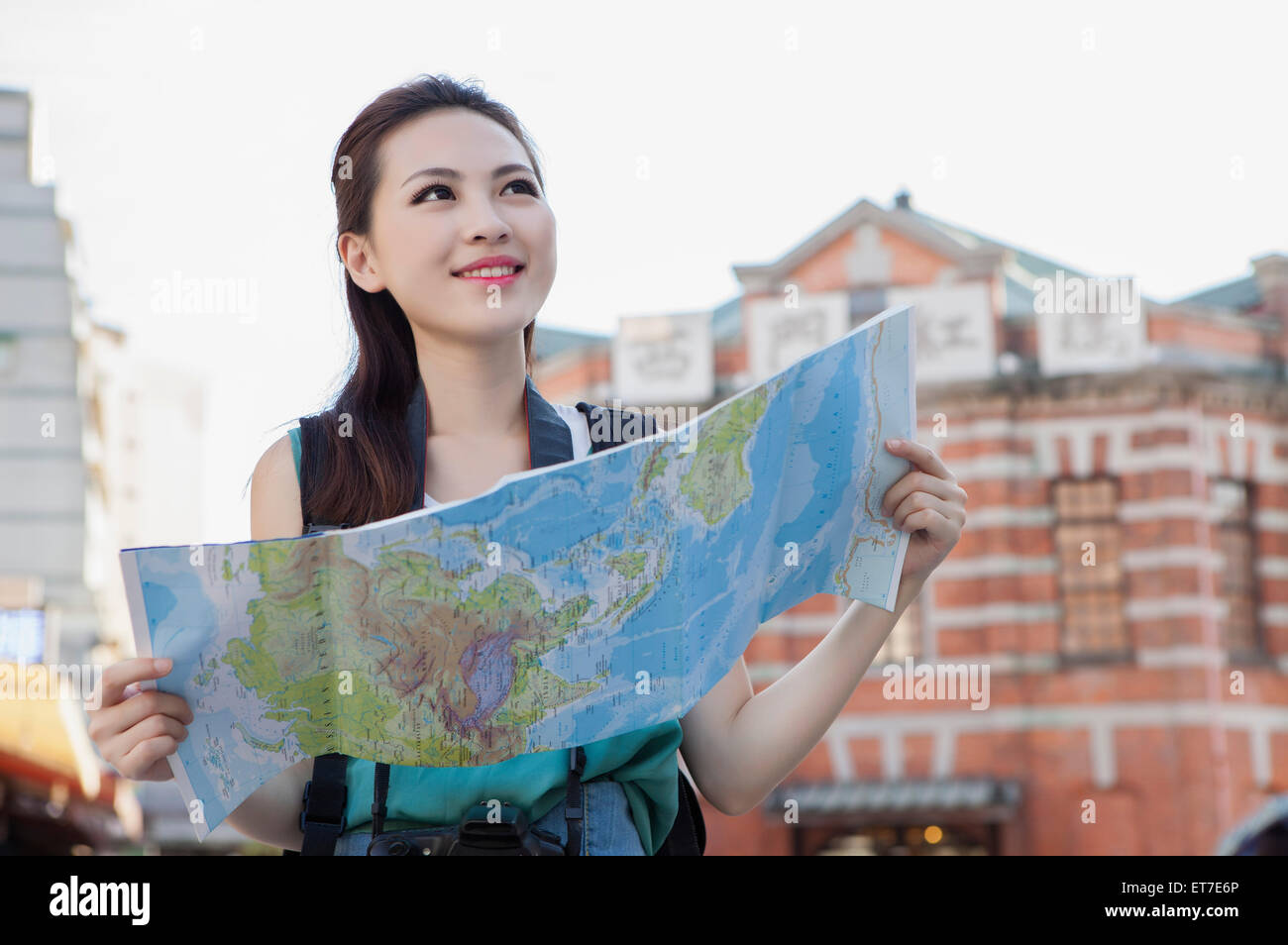Young woman holding a map and looking up with smile Stock Photo - Alamy