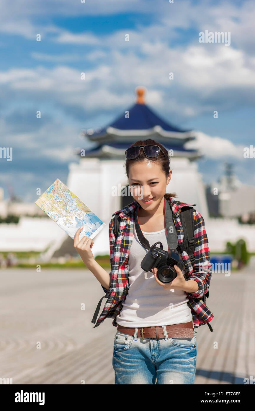 Young woman holding camera and looking down with smile Stock Photo - Alamy