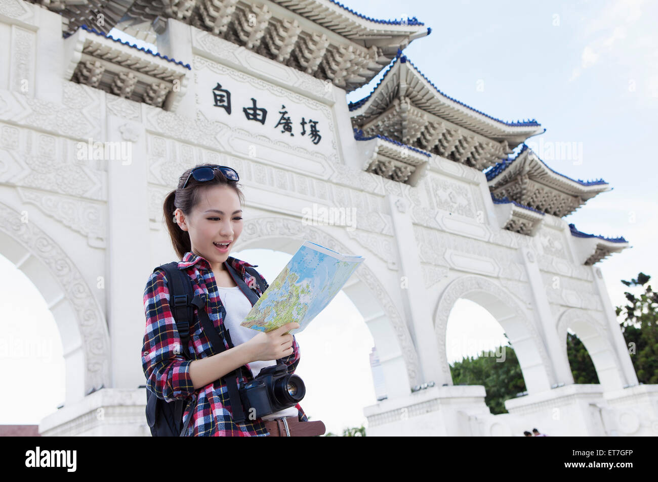 Young woman holding a map and looking down with smile Stock Photo - Alamy