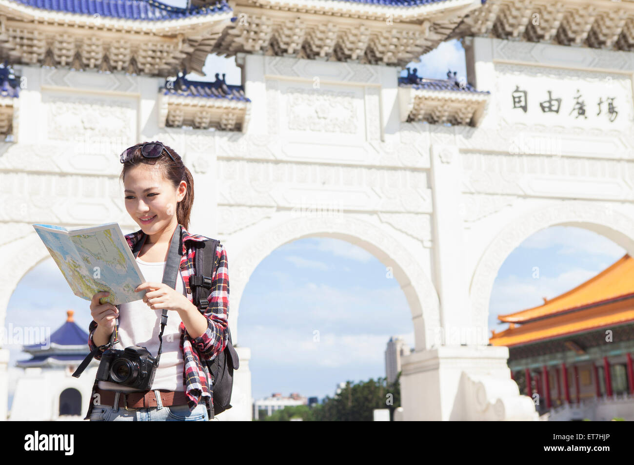 Young woman holding a map and looking down with smile Stock Photo - Alamy