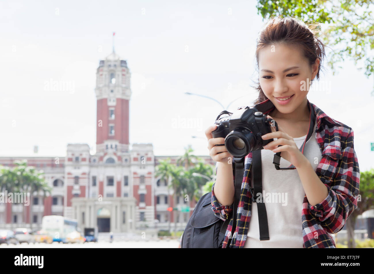 Young woman holding camera and looking down Stock Photo - Alamy