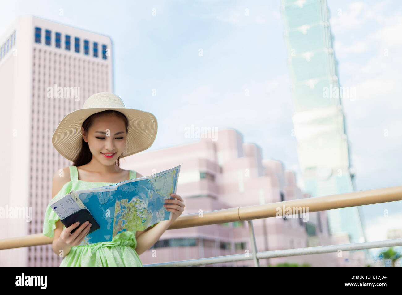 Young woman holding a map and looking down with smile Stock Photo - Alamy
