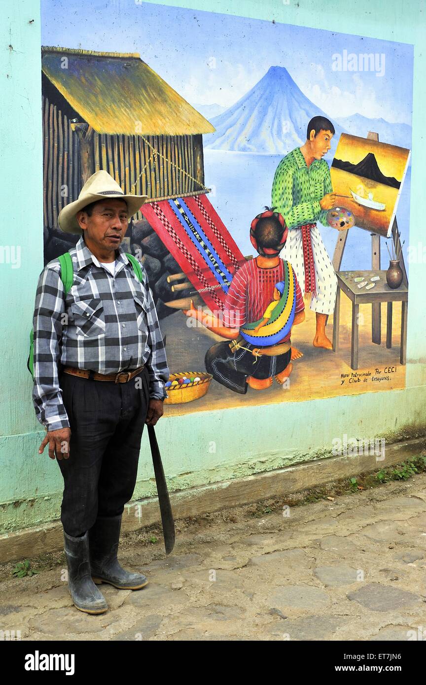 Mann steht mit Machete in der Hand vor Gemaelde an einer Haeuserwand ...