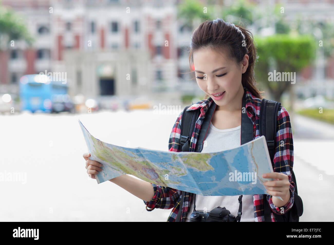 Young woman holding a map and looking down with smile Stock Photo - Alamy