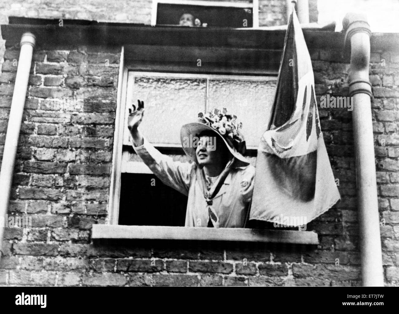 A Suffragette leaning out of a window, waving and holding a banner ...