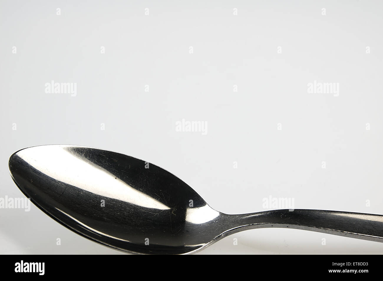 Metal spoon lying on the kitchen, white table Stock Photo - Alamy