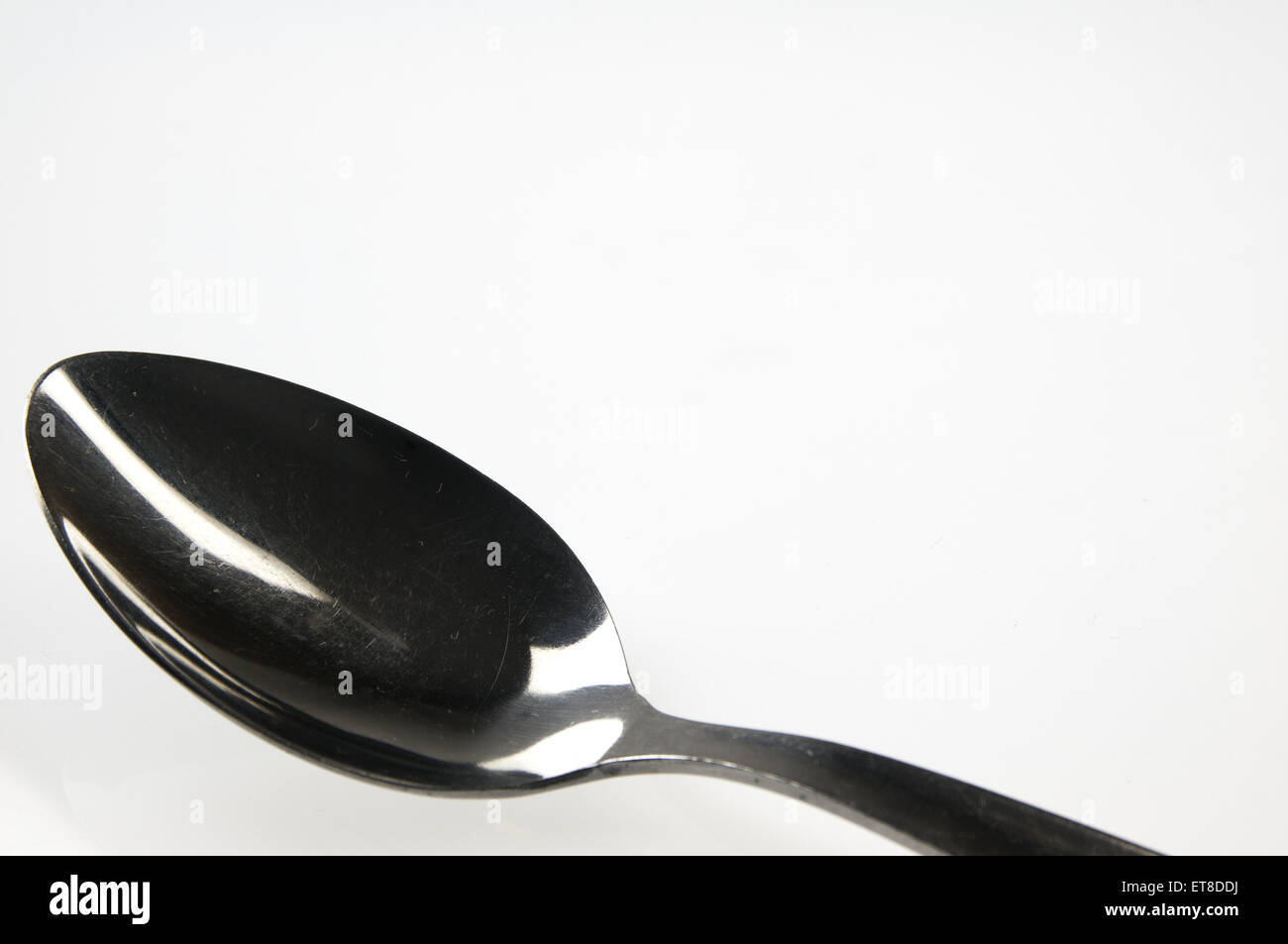 Metal spoon lying on the kitchen, white table Stock Photo - Alamy