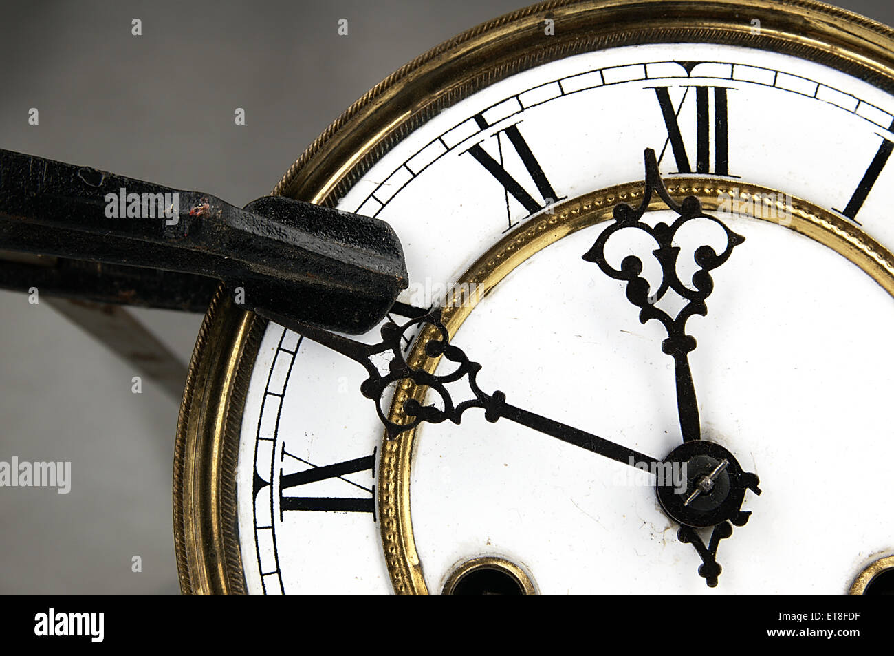 Carpenter clamp blocks the clock. Old clock-face with Roman numerals ...