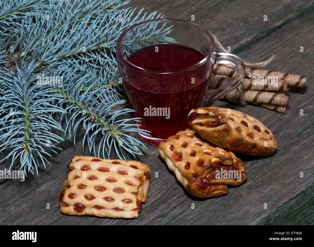 the glass of tea decorated with different cookies and a branch of a fir ...