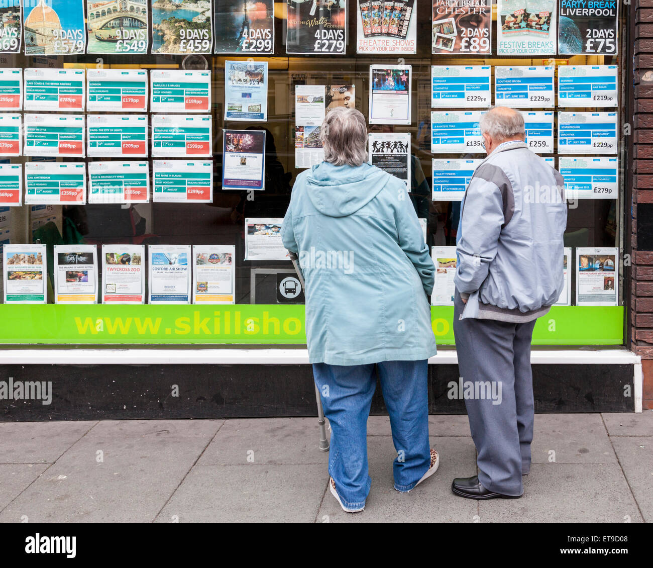 Travel agency window. Older people looking at holiday information at a ...