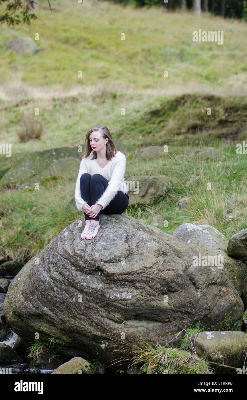 Young woman sat on the rocks Stock Photo - Alamy